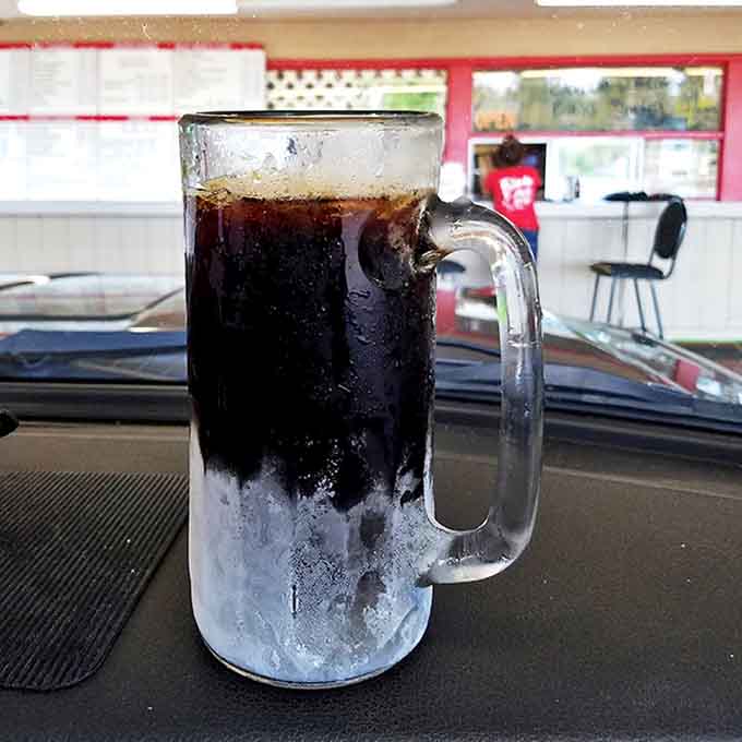 A frosty mug of homemade root beer sits proudly on the dashboard, condensation forming like nature's own advertisement for refreshment.
