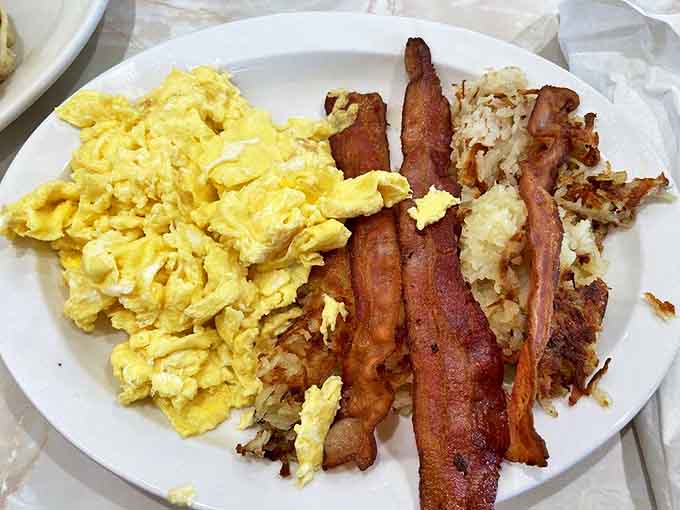 The breakfast trinity that's launched a thousand productive days: fluffy scrambled eggs, bacon cooked to that perfect crisp-yet-chewy state, and hash browns worth getting out of bed for.