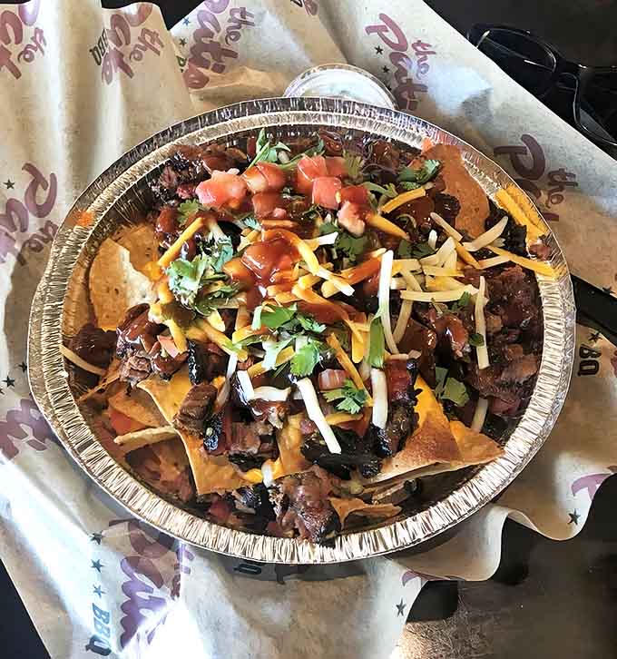 BBQ nachos that redefine indulgence &ndash; a mountain of crispy chips supporting tender brisket, melted cheese, and fresh toppings in perfect harmony.