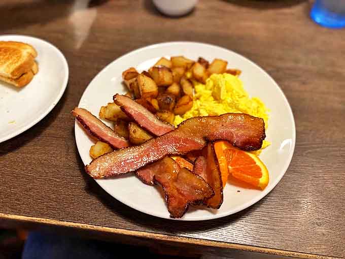 Crispy-edged bacon with that perfect chew, scrambled eggs that defy gravity, and home fries that could make a potato farmer weep with joy.
