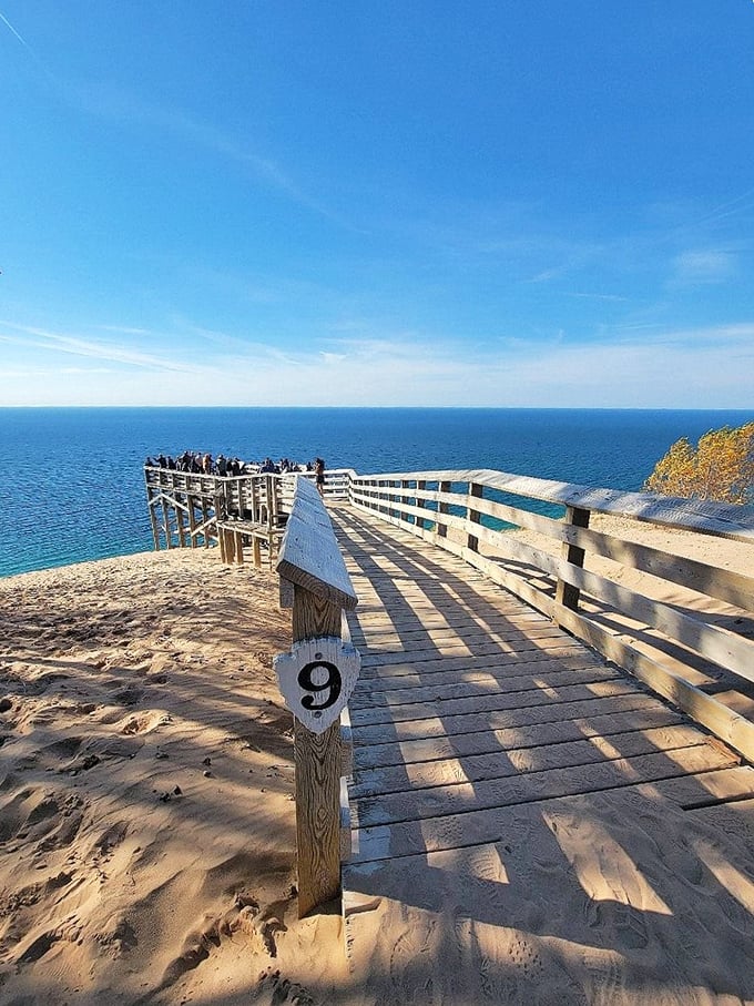The wooden boardwalk stretches across sandy dunes like an invitation to adventure, with Lake Michigan's blue expanse playing peekaboo in the distance.