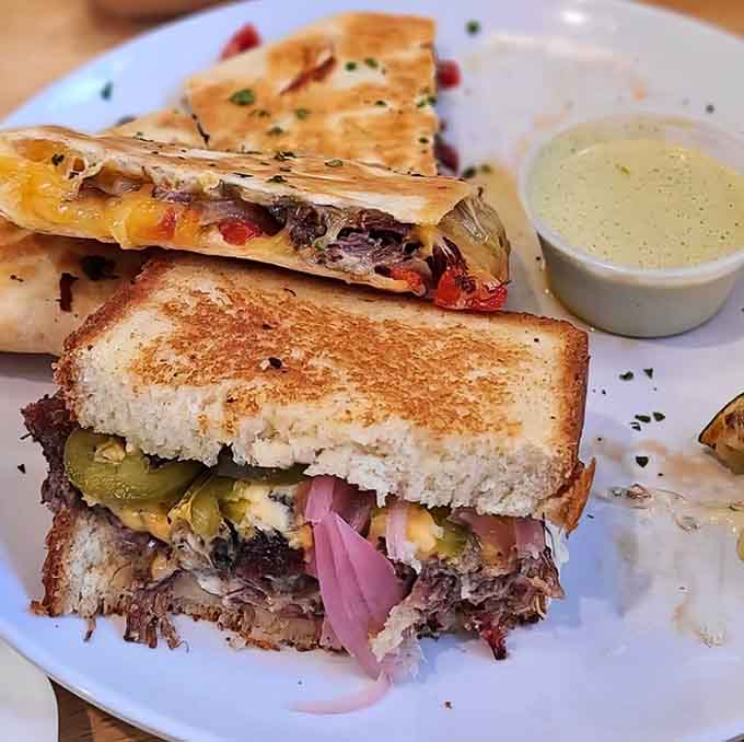 Behold the sandwich that launched a thousand return visits, where brisket meets bread in perfect harmony with pickles and sauce.