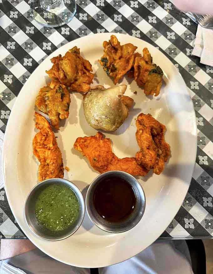 Crispy pakoras arranged like a delicious clock face, with mint and tamarind chutneys standing by for essential dipping duty.