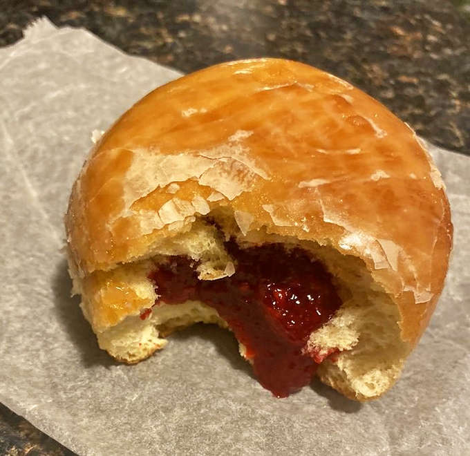 Bite into tradition with this raspberry-filled pączki. That vibrant jam center bursting through soft dough is what sweet dreams are made of.