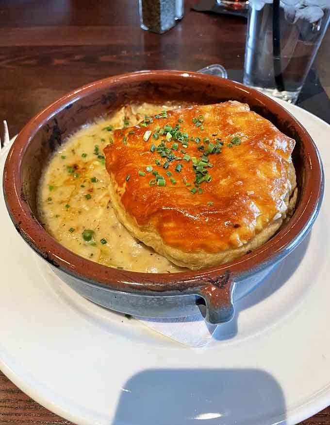 That flaky pastry dome conceals a treasure trove of tender chicken and vegetables swimming in creamy, savory gravy.