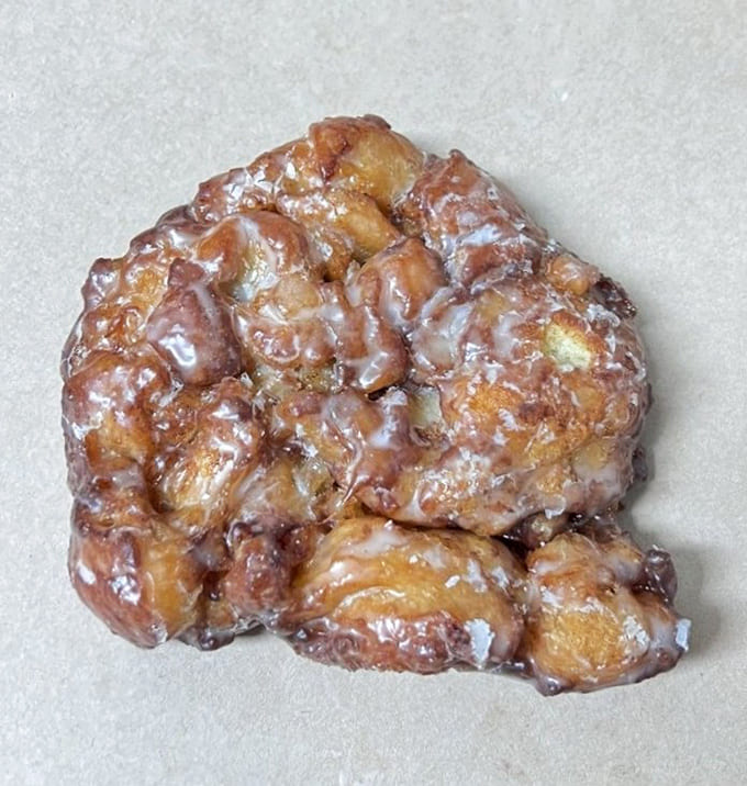 The apple fritter: a magnificent misshapen marvel that laughs in the face of symmetry while delivering caramelized chunks of apple paradise.