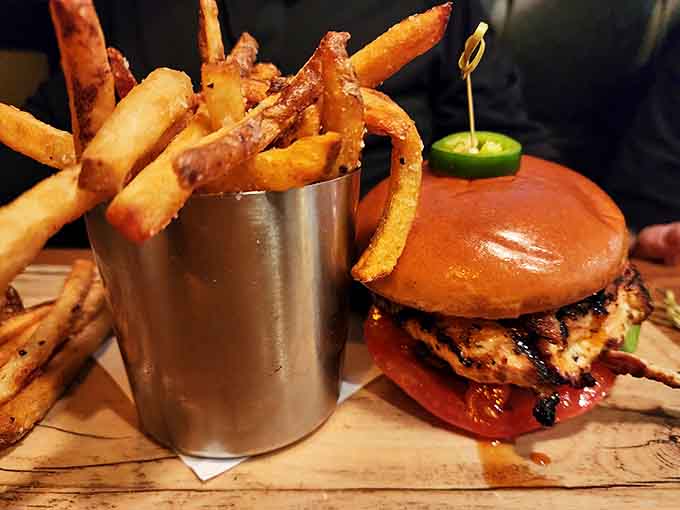 That burger stands tall and proud next to a tower of golden fries, proving this kitchen knows its way around all things delicious.