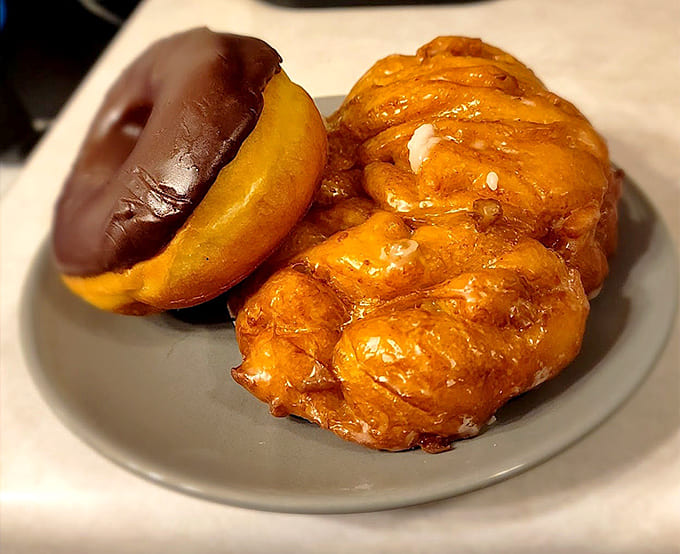 Size comparison: one apple fritter versus a regular donut, proving that bigger really is better when it comes to fried dough.