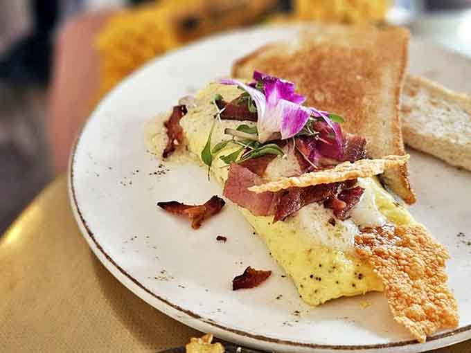 Breakfast alchemy at its finest: a perfectly cooked omelet adorned with crispy bacon and fresh herbs that elevates morning protein to an art form.