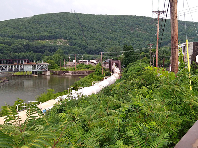 Industrial heritage meets natural beauty where the pipeline stretches alongside the river, a reminder of Vermont's resourceful past.