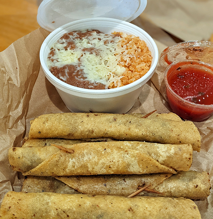 A complete meal that hits all the right notes – crispy rolled tacos, hearty beans, Spanish rice, and that essential side of salsa for customized heat.