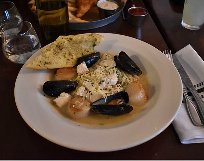 Ocean neighbors reunite on your plate &ndash; tender scallops and plump mussels swimming in a broth you'll want to bottle and take home.