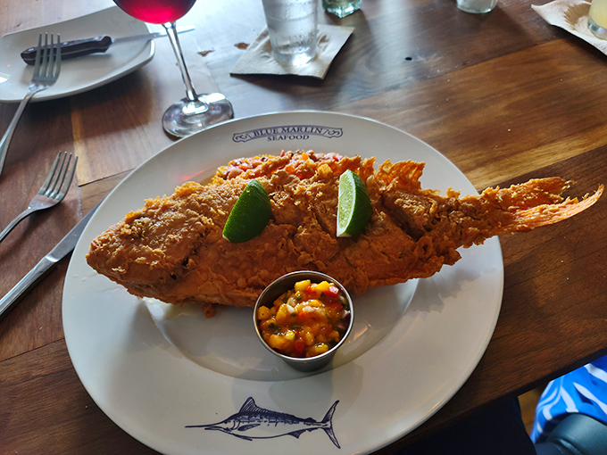 This whole fried snapper arrives like a crispy golden trophy, perfectly seasoned and accompanied by bright lime and mango salsa.