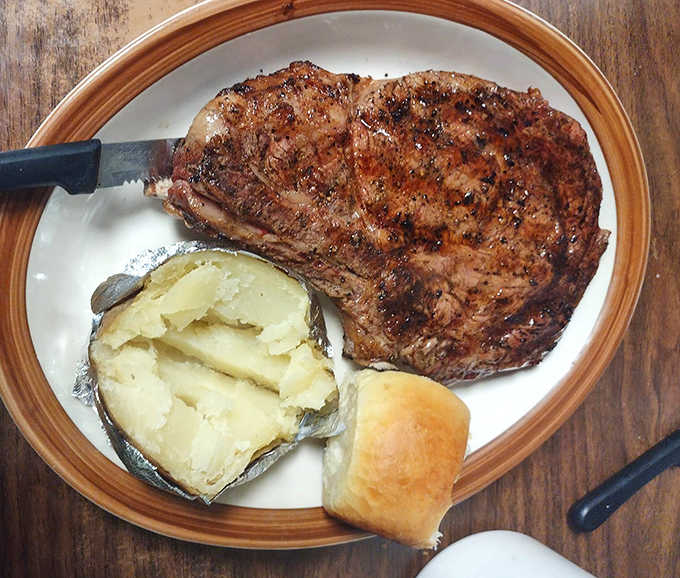 A perfectly grilled steak with fluffy baked potato and fresh bread proves this place does more than just fish fry magic.