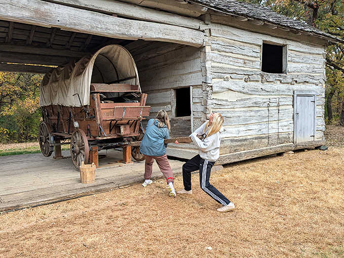 Young explorers discover the joys of pioneer life, pushing a covered wagon with the enthusiasm only childhood allows.