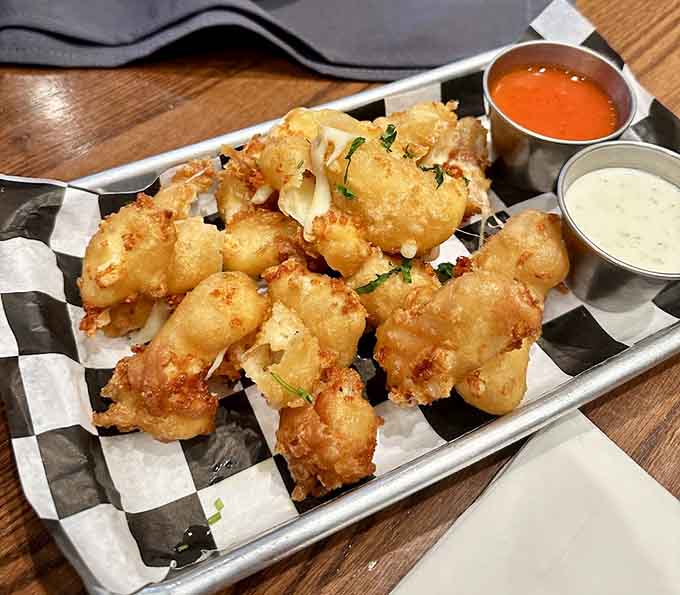 Golden cheese curds arrive like crispy little treasure chests, each one hiding molten cheese that'll make you forget Wisconsin exists.