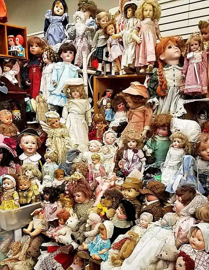 An army of antique dolls stands in silent formation, their porcelain faces and glass eyes telling stories of playtimes from generations past.