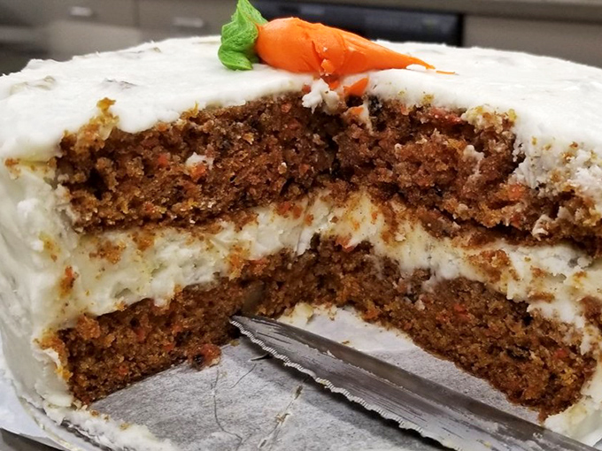 Carrot cake perfection: spiced layers embracing cream cheese frosting that strikes the elusive balance between tangy and sweet, topped with a playful carrot.