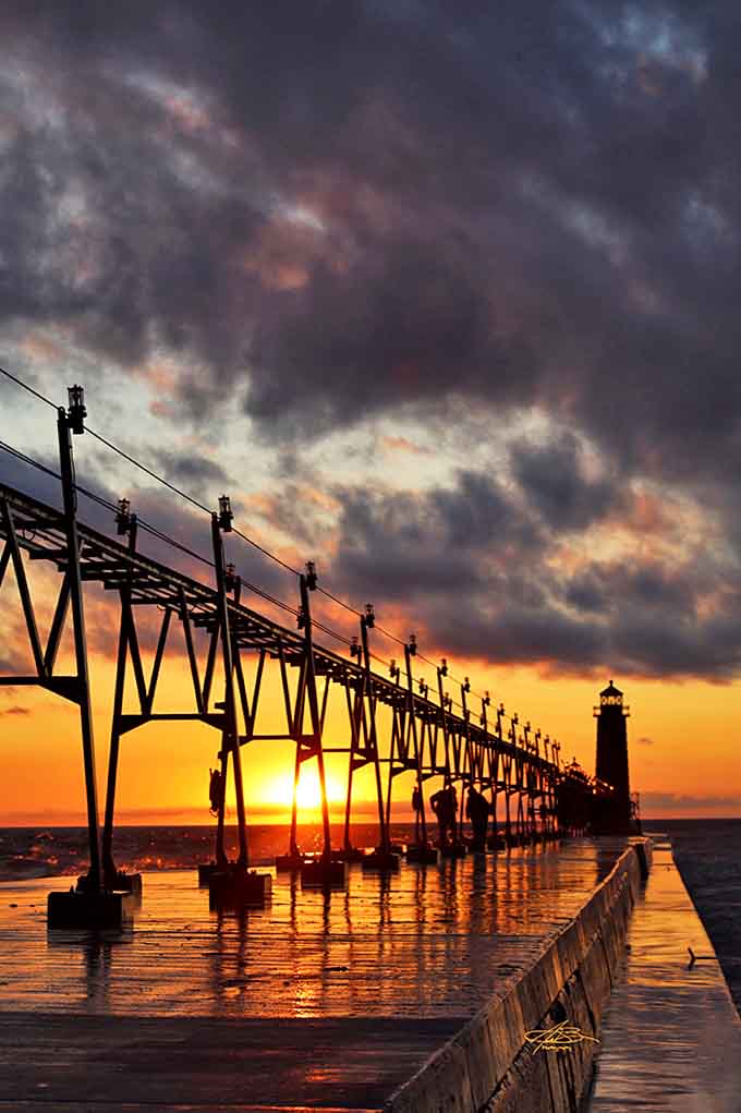 Silhouetted against a fiery sunset, the lighthouse and catwalk create a scene so perfect it looks like a painting come to life.