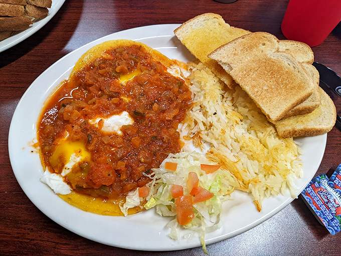 Huevos Rancheros that would make any abuela proud – eggs nestled in spicy tomato sauce with rice and fresh vegetables creating the perfect breakfast symphony.