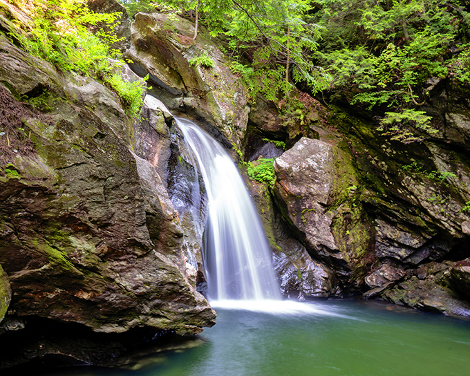 Bingham Falls cascades into a clear emerald pool, offering a refreshing woodland escape on warm Vermont days.