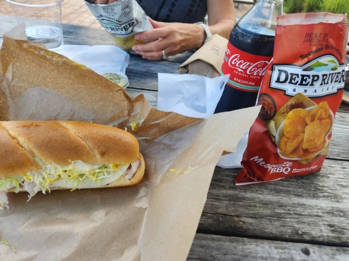 The perfect Vermont picnic spread, a hearty sandwich, craft soda, and kettle chips, ready for riverside dining or mountain views.