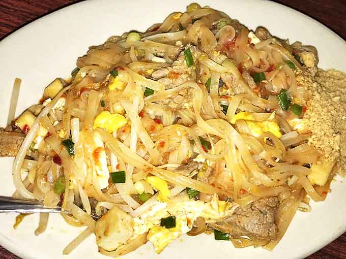 A close-up of their legendary Pad Thai reveals the perfect tangle of noodles, eggs, and protein, sprinkled with crushed peanuts for that authentic crunch.