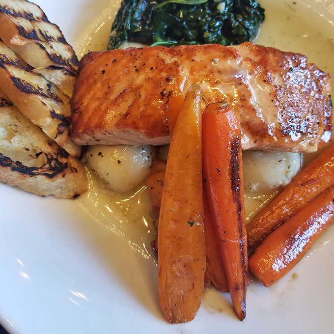 Another salmon masterpiece featuring roasted carrots and vibrant greens in a delicate sauce &ndash; comfort food elevated to fine dining status.