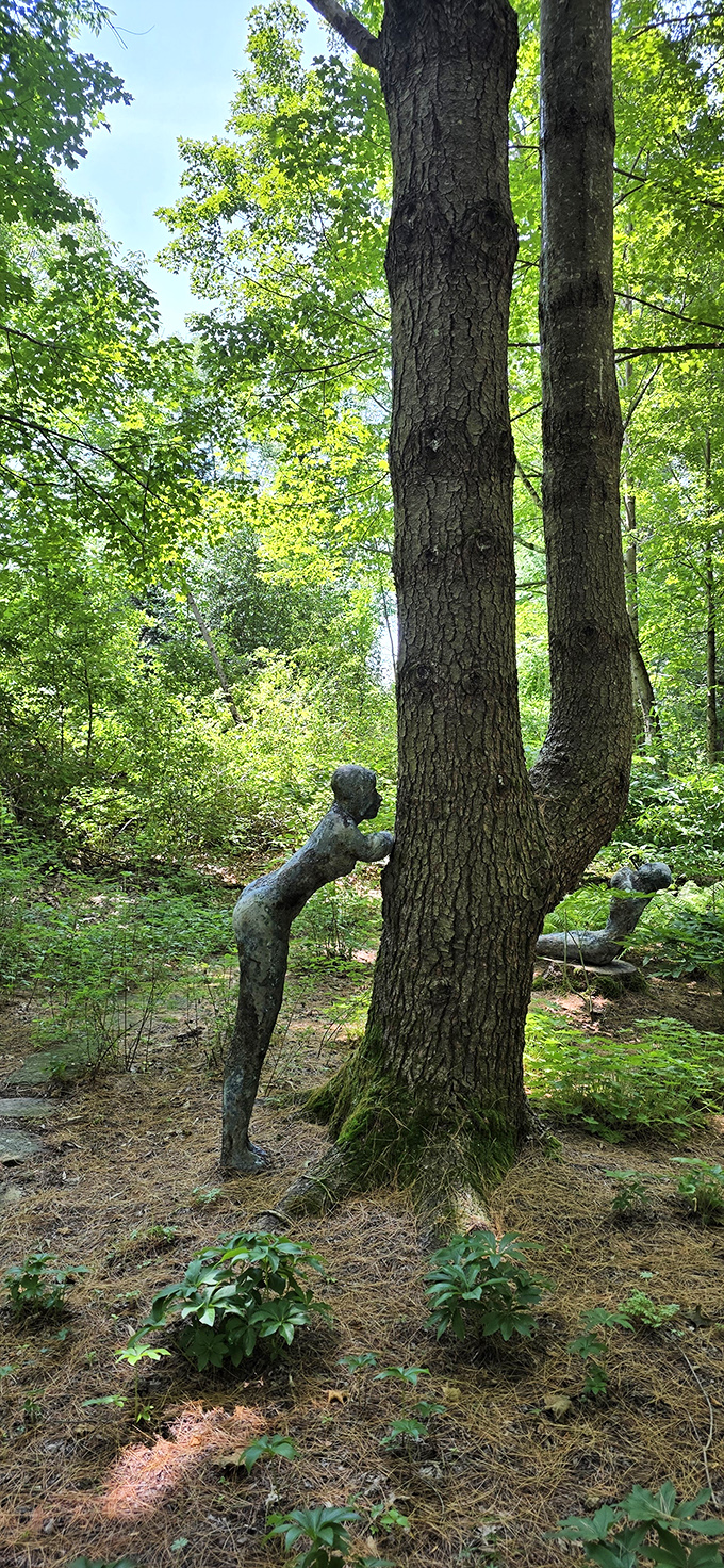 Nothing says "contemplative art" quite like a sculpture casually leaning against a tree like it's waiting for a bus.