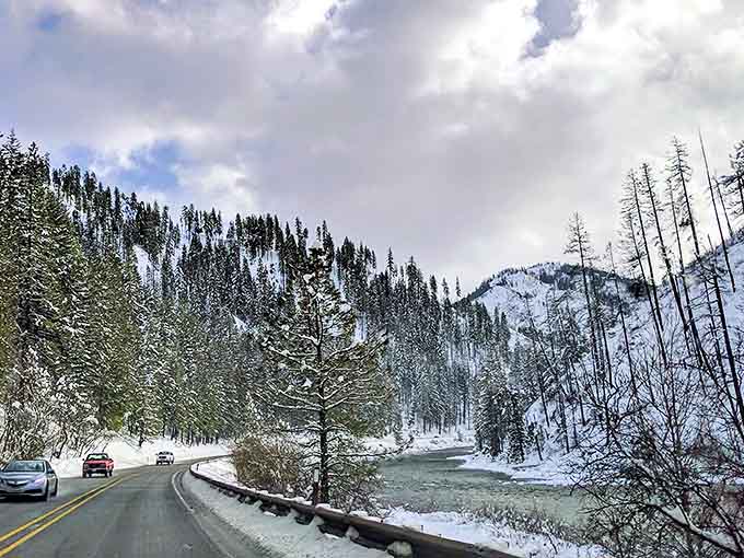 Winter transforms US-2 into a snow-globe fantasy, where evergreens wear white coats and the road cuts through nature's frozen art.