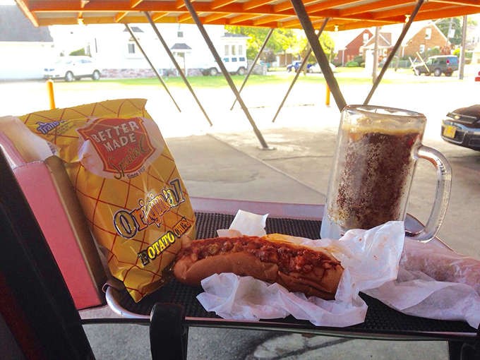 The complete Monroe's experience: a chili dog nestled beside crispy chips and a frosty mug of root beer – America's comfort food trinity.