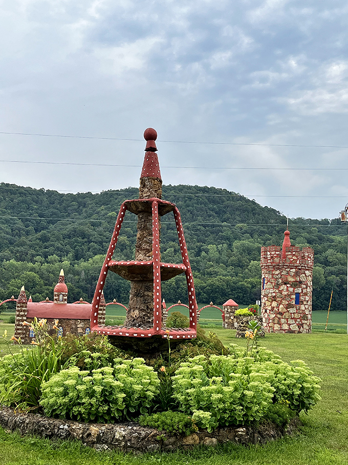 Stone towers and decorative structures rise from the grass, creating a folk art wonderland that seems plucked from a storybook.