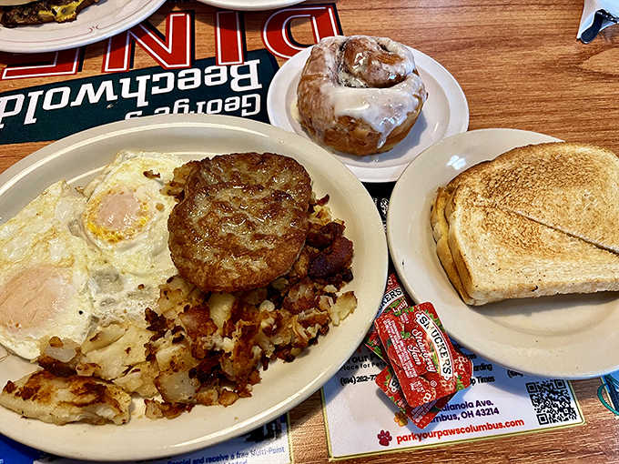 Morning glory on a plate: a hearty breakfast featuring eggs and home fries, with a cinnamon roll that's basically dessert masquerading as breakfast &ndash; nobody's complaining.