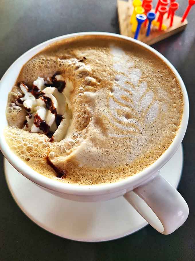 This cappuccino's swirls of chocolate sauce aren't just decoration – they're a hypnotic device to distract you while cats plot world domination.