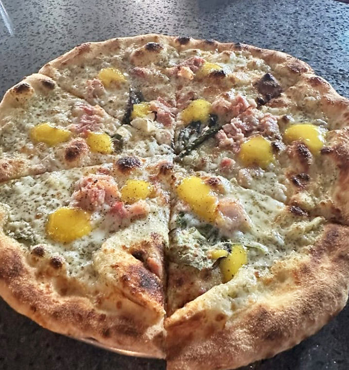 The Carbonara pizza reimagines pasta's greatest hit, with pancetta and egg yolk creating a symphony of richness.