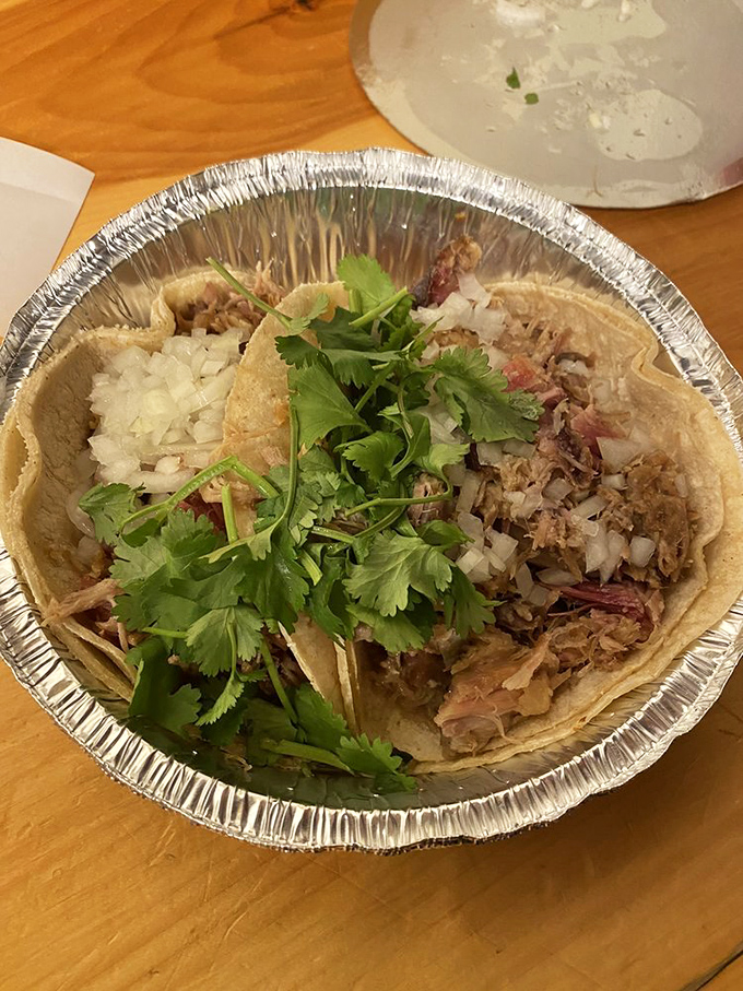 Slow-cooked pork shoulder shreds at the slightest touch, topped with fresh onions and cilantro for that perfect flavor balance.