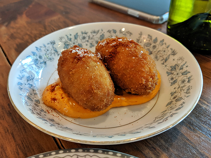 Golden croquettes perch on a vibrant sauce, their crispy exteriors giving way to creamy interiors &ndash; Spain's perfect answer to the humble hush puppy.