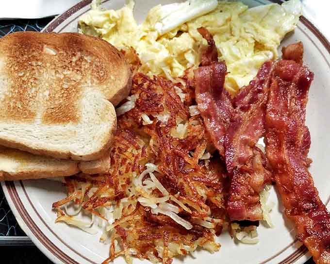 The breakfast trinity: crispy-edged eggs, hash browns with the perfect shatter-factor, and bacon cooked to that mythical middle ground between chewy and crisp.