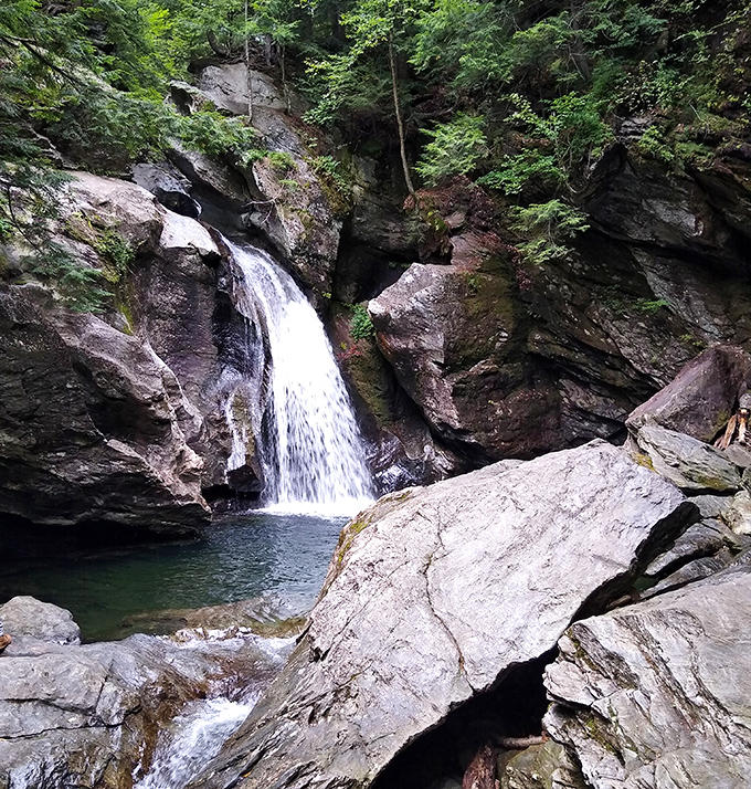 Summer's emerald curtain parts to reveal Bingham Falls in full flow, a refreshing sight that beckons overheated hikers.
