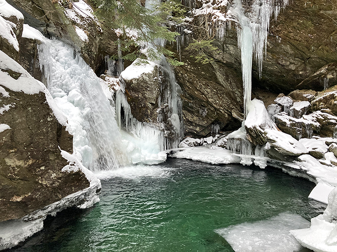 Winter transforms Bingham Falls into a sparkling ice fortress, with frozen columns and bright turquoise water below.