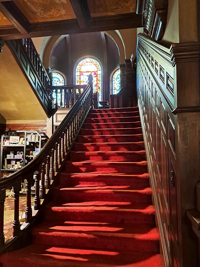 The grand staircase, bathed in colored light from stained glass windows, has probably never witnessed anyone sliding down its banister. Probably.