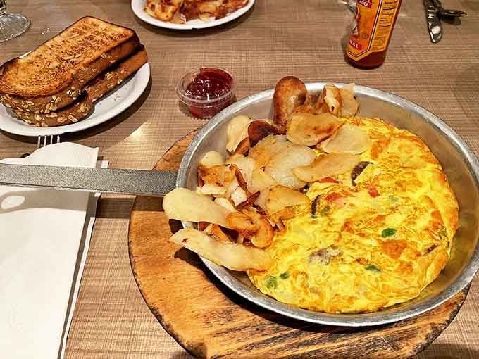 That omelet is fluffier than a cloud and packed with more ingredients than a Greek family reunion, served in a skillet for maximum drama.