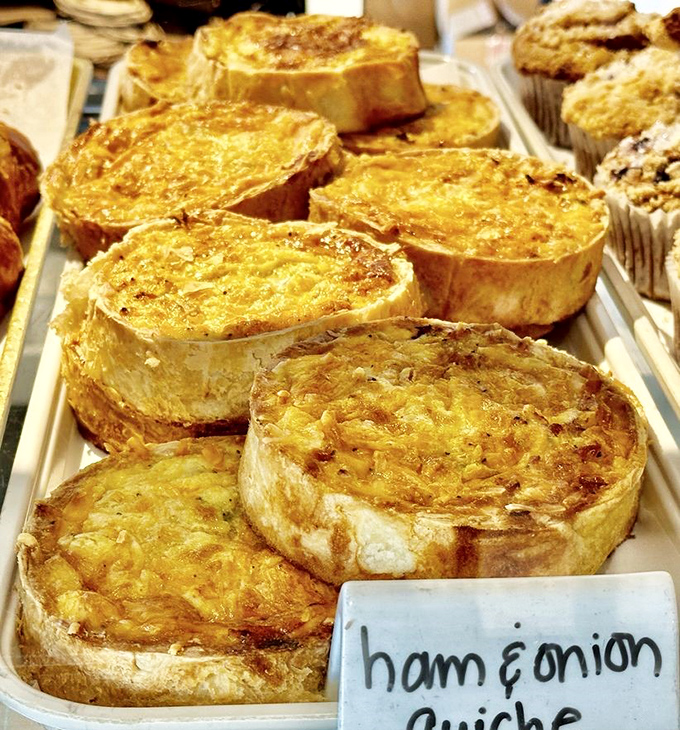 Golden ham and onion quiches sit warm and inviting, their flaky crusts promising cozy comfort.