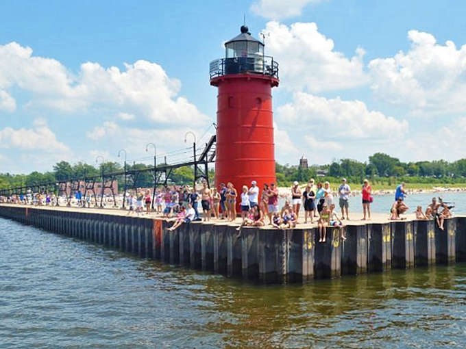 The iconic red lighthouse stands sentinel at South Pier, where generations have gathered to witness Lake Michigan's legendary sunsets.