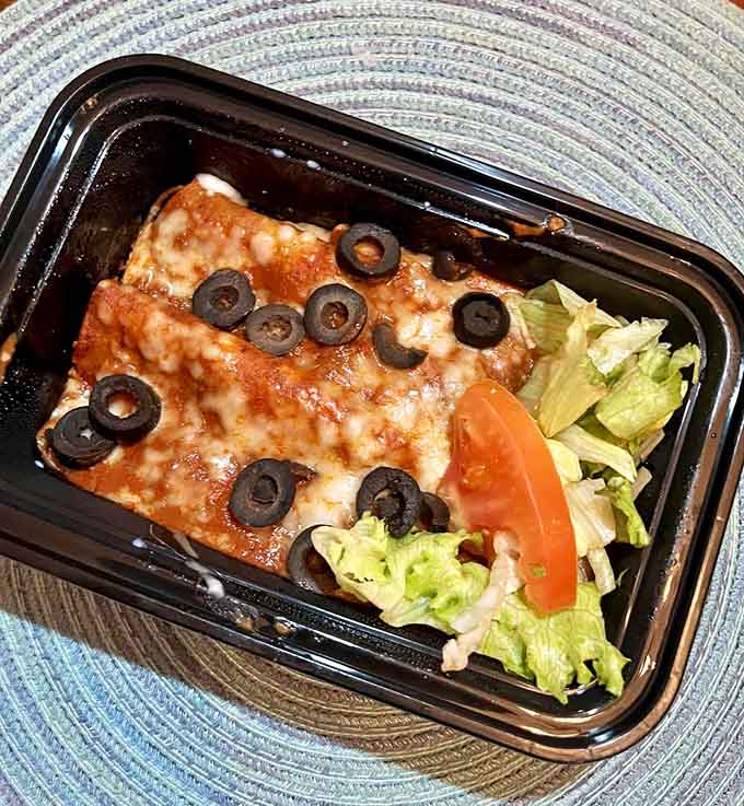 Enchiladas swimming in sauce with melted cheese and olives, comfort food that hugs you from the inside out.