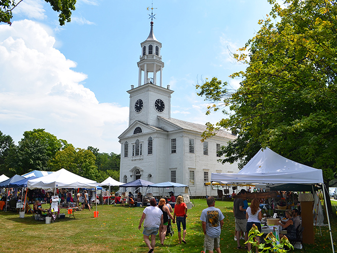 The town green comes alive during community events, where white tents and the historic church create a quintessential New England tableau.