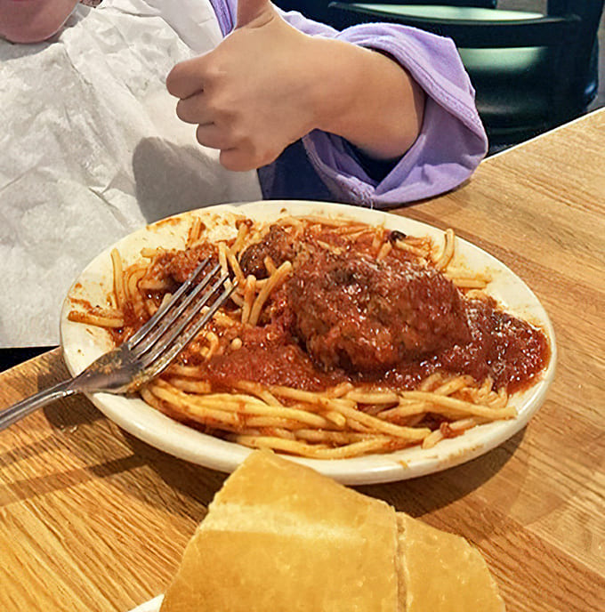 A young diner gives the universal sign of approval. Nothing validates good food like the honest enthusiasm of a child's double thumbs-up.