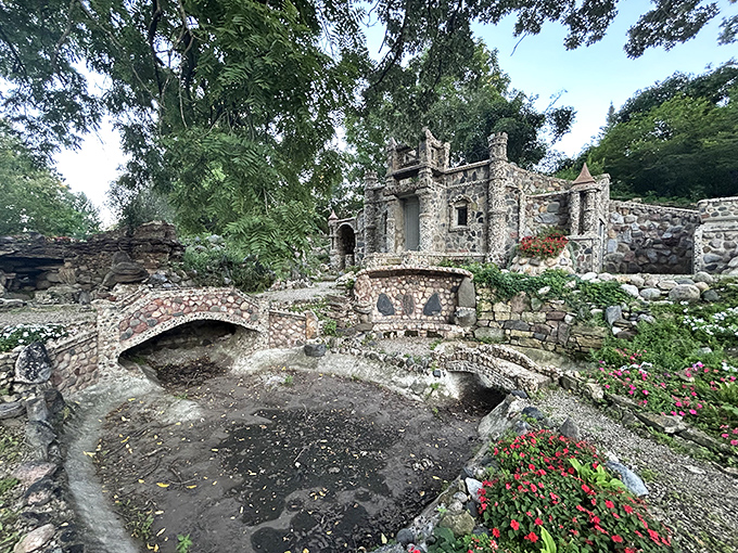 This stone bridge arches over the garden path with careful craftsmanship, serving no practical purpose except making visitors smile and photographers very, very happy with their shot selection.