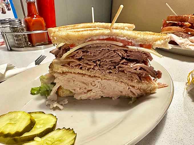 The turkey club sandwich stands tall and proud, a skyscraper of thinly sliced meat that requires a strategic approach to eating.