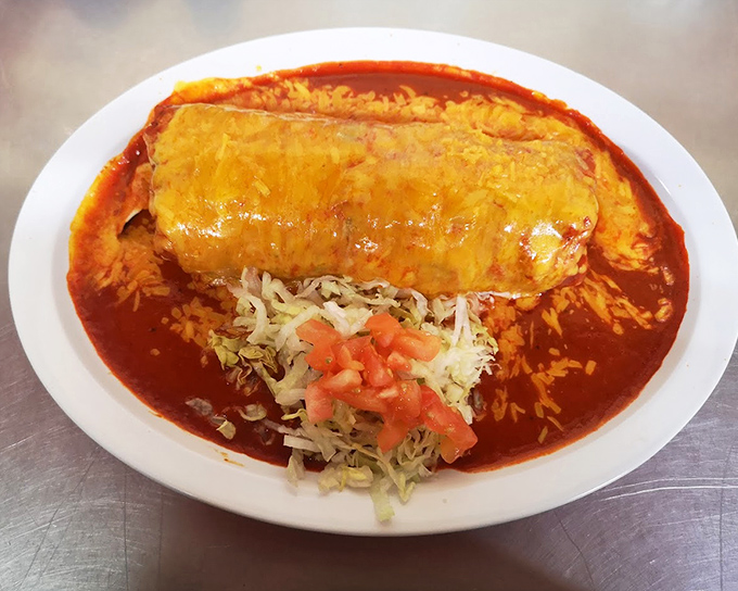 A burrito that's practically swimming in rich red sauce, topped with melted cheese and flanked by fresh lettuce and tomato. This isn't fast food – it's slow food done right.